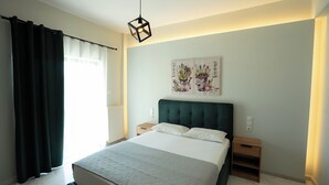 Quarto moderno com cama grande, mesa de cabeceira, luminária pendente e uma obra de arte na parede.