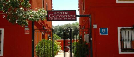 Um edifício vermelho com uma placa indicando 'Hostal Cervantes' e um portão.