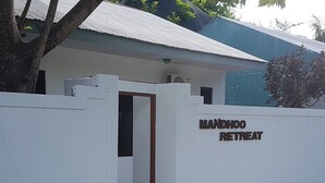 Uma entrada com portão para um refúgio, com uma placa indicando "MANDHOO RETREAT".