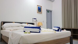 Quarto de hotel com cama, abajur, porta e um quadro na parede.
