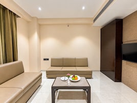 Uma sala de estar moderna com um sofá, uma mesa de centro com frutas e uma televisão de tela plana na parede.