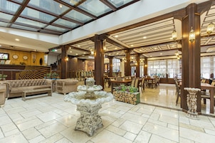 Um hall amplo com teto alto, vigas de madeira e uma fonte central.