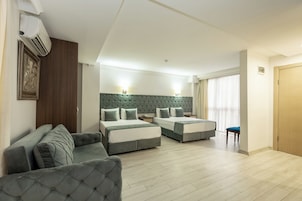 Quarto de hotel com duas camas, um sofá, uma mesa pequena e uma cadeira.