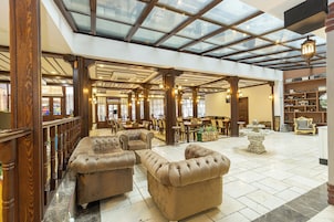 Um hall amplo com teto alto, cobertura de vidro e área de estar com sofás confortáveis.