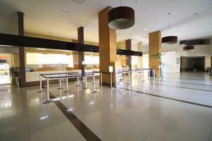 Um hall espaçoso com balcão de recepção, uma barreira azul e uma luminária pendente grande.