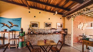 Uma sala de jantar rústica com móveis de madeira, parede de tijolos e decorações penduradas.
