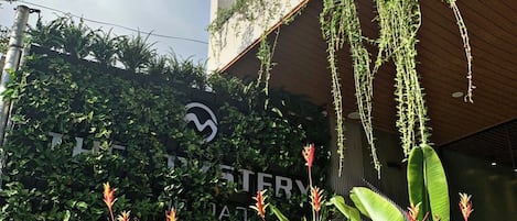 Um edifício com uma placa que diz 'THE FINEST', rodeado por vegetação exuberante e plantas.