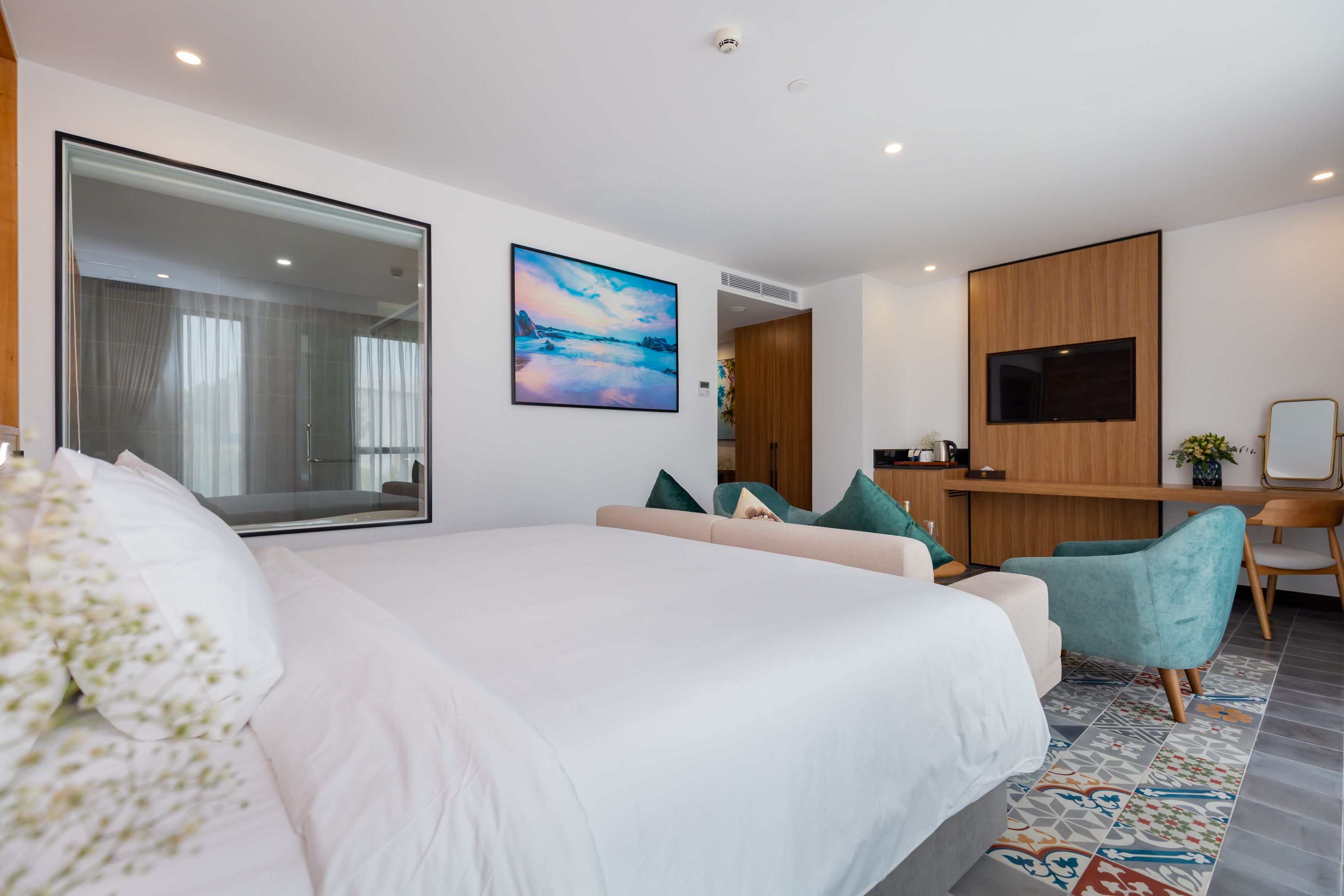 Quarto de hotel moderno com uma cama grande, uma escrivaninha, uma televisão e vista para o banheiro.