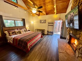 Um quarto aconchegante com uma cama, lareira e ventilador de teto.