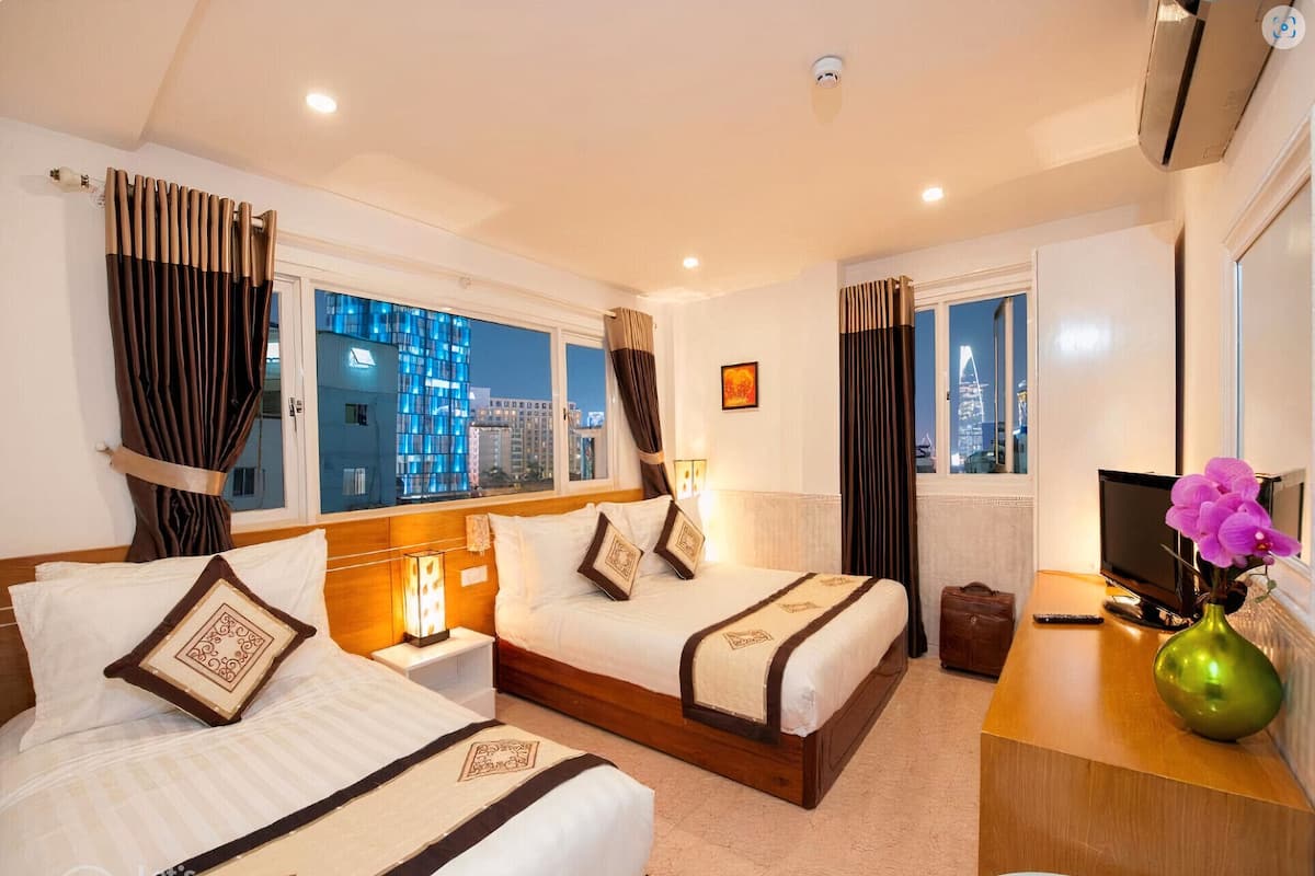 Quarto de hotel com duas camas, uma mesa, uma televisão e vista para a cidade.