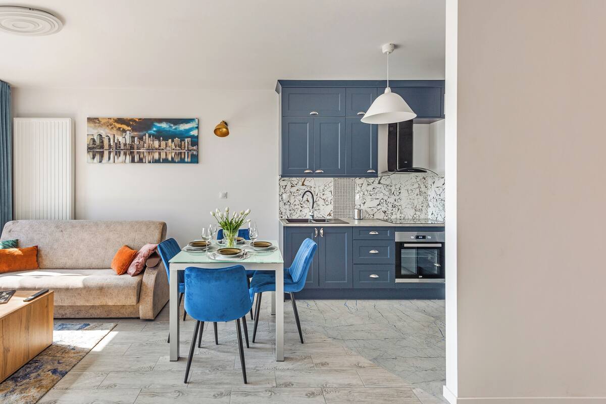 Uma sala de estar moderna com sofá, mesa de centro e área de jantar com cadeiras e mesa posta para uma refeição.