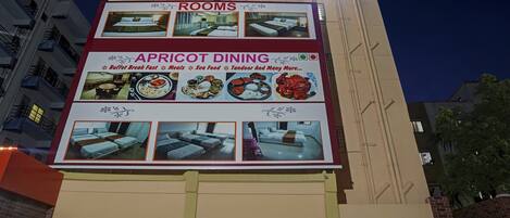 Placa de hotel anunciando quartos e o restaurante Apricot, com café da manhã em buffet, refeições, frutos do mar, tandoor e muito mais.