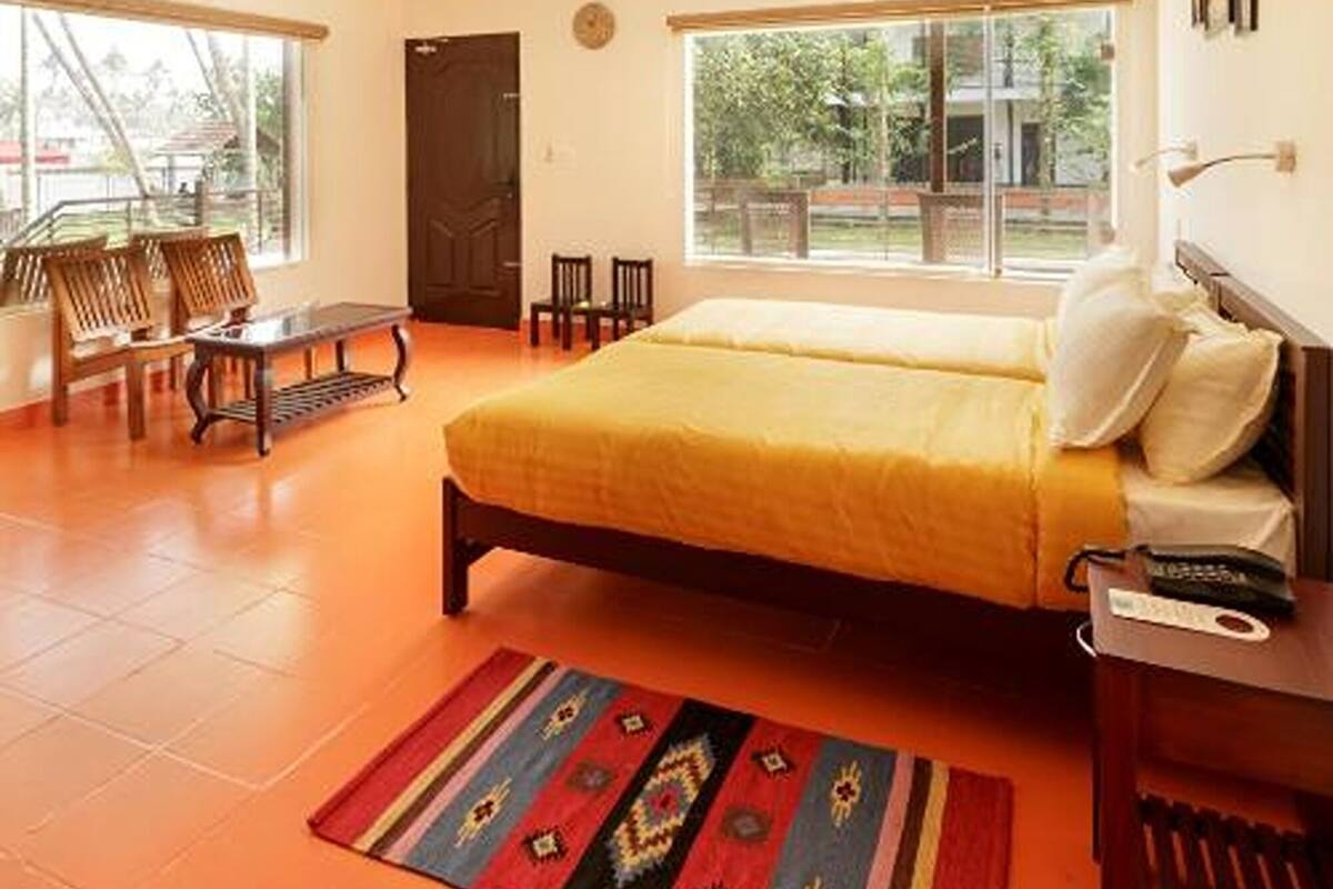 Um quarto espaçoso com uma cama grande, duas cadeiras, uma mesinha e um ventilador de teto.