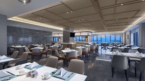 Um restaurante moderno com pé-direito alto, paredes de mármore e vista para a cidade.