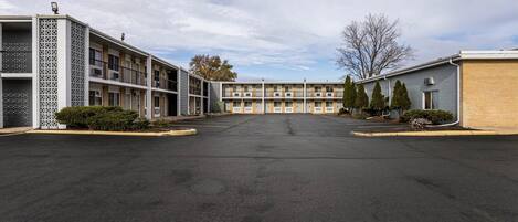 Um motel com pátio central, edifícios de vários andares e estacionamento.