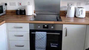 Uma cozinha moderna com armários brancos, eletrodomésticos de aço inoxidável, forno embutido e micro-ondas.