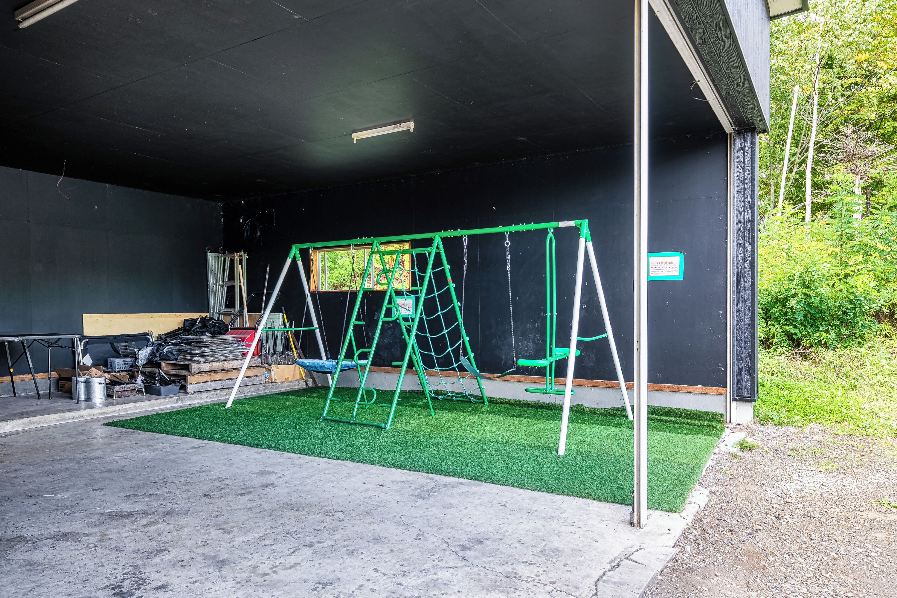 Um espaço ao ar livre coberto com balanço, grama sintética e piso de concreto.