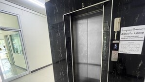 Elevador em edifício moderno com parede de mármore e placa indicando um preço de 1.000B.