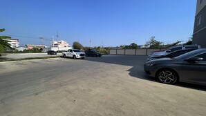 Um estacionamento com vários carros e um prédio ao fundo.