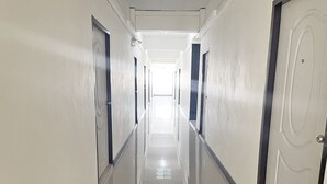 Um corredor comprido e estreito com portas em ambos os lados, dando acesso a quartos.