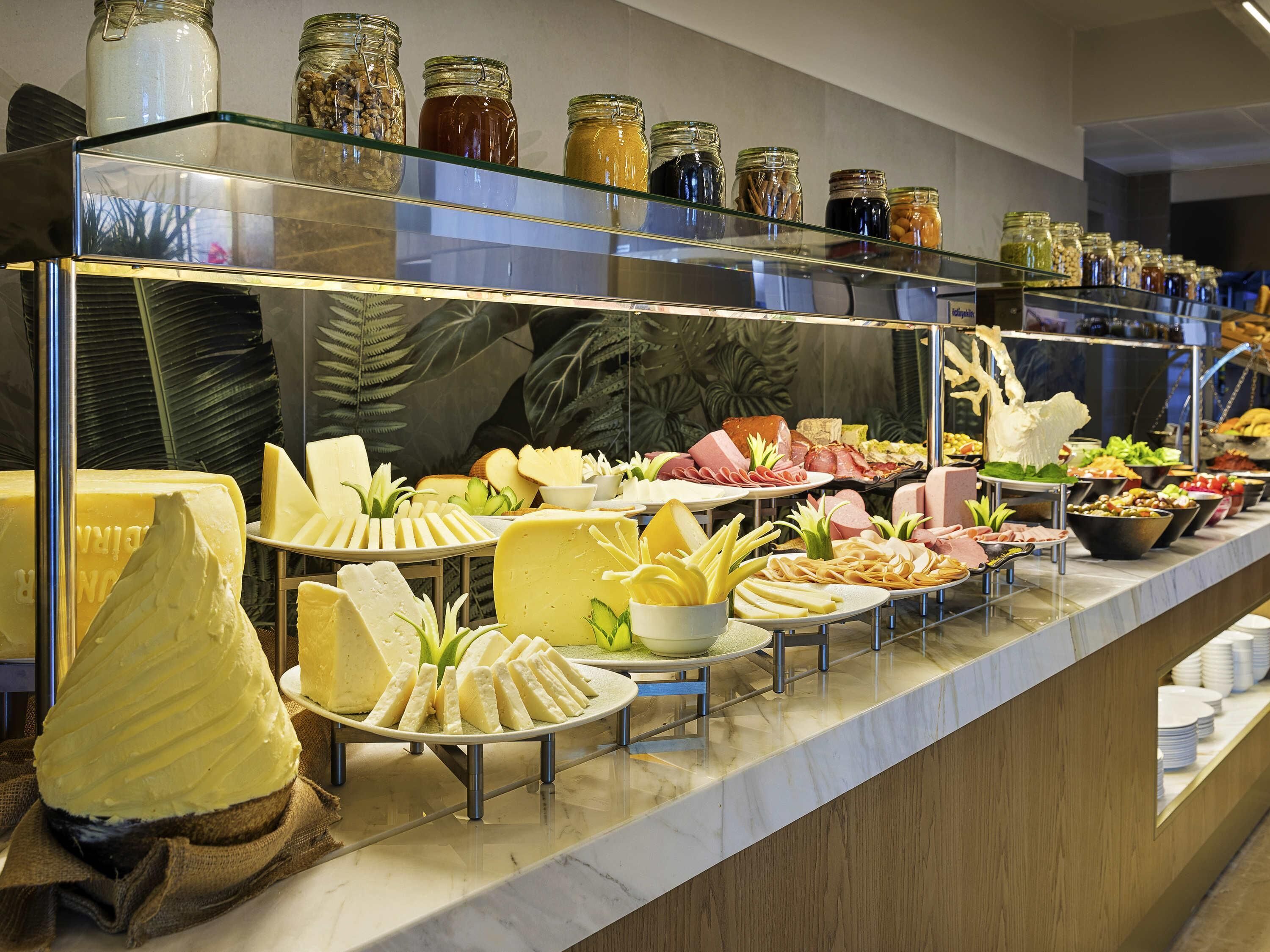 Buffet com diversos queijos, carnes e frutas.