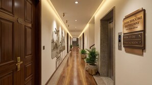 Corredor de hotel com portas de madeira, uma placa indicando a Expressway Yashobhoomi e uma placa com os números de quartos 201 a 210 e uma sala de estar.