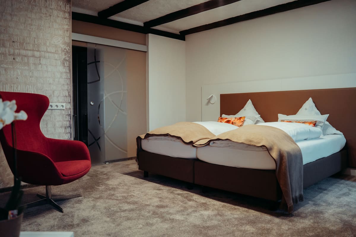 Um quarto moderno com uma cama de casal, uma cadeira vermelha e uma janela grande.