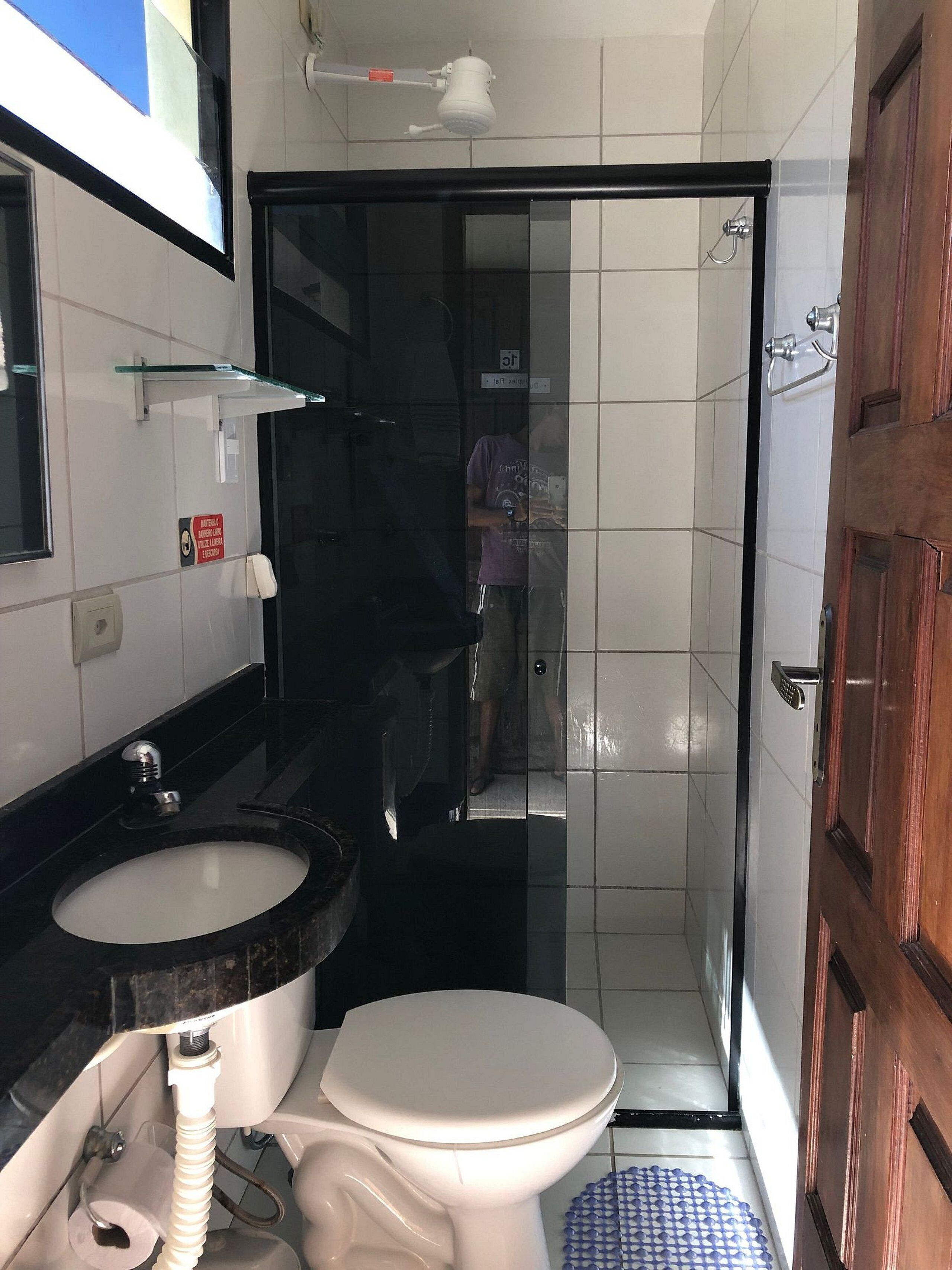 Casa de banho compacta com sanita, lavatório e chuveiro.