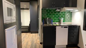 Cozinha moderna com armários pretos, painel de parede verde e máquina de lavar louça.