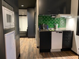 Cozinha moderna com armários pretos, painel de parede verde e máquina de lavar louça.