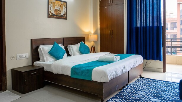 Quarto com cama, ventilador de teto, mesa de cabeceira, guarda-roupa e janela com cortinas.
