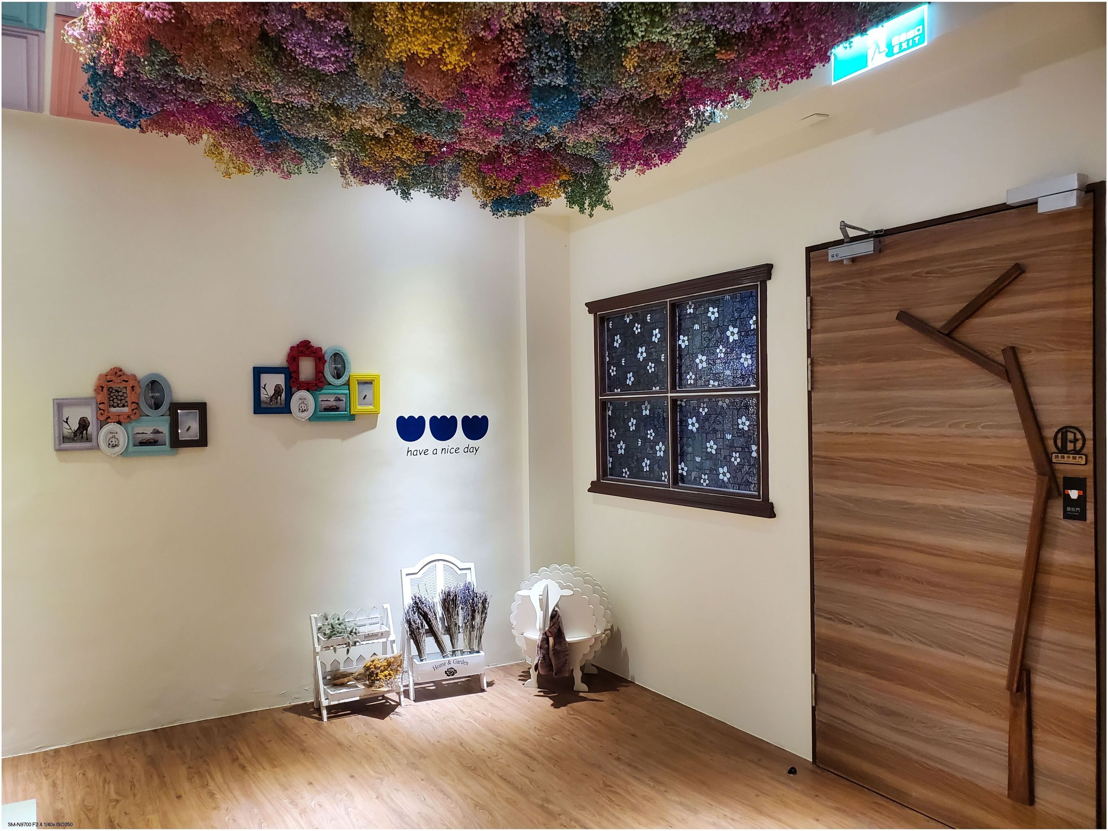 Quarto com piso de madeira, teto decorativo, janela com padrão floral e porta com moldura de madeira.