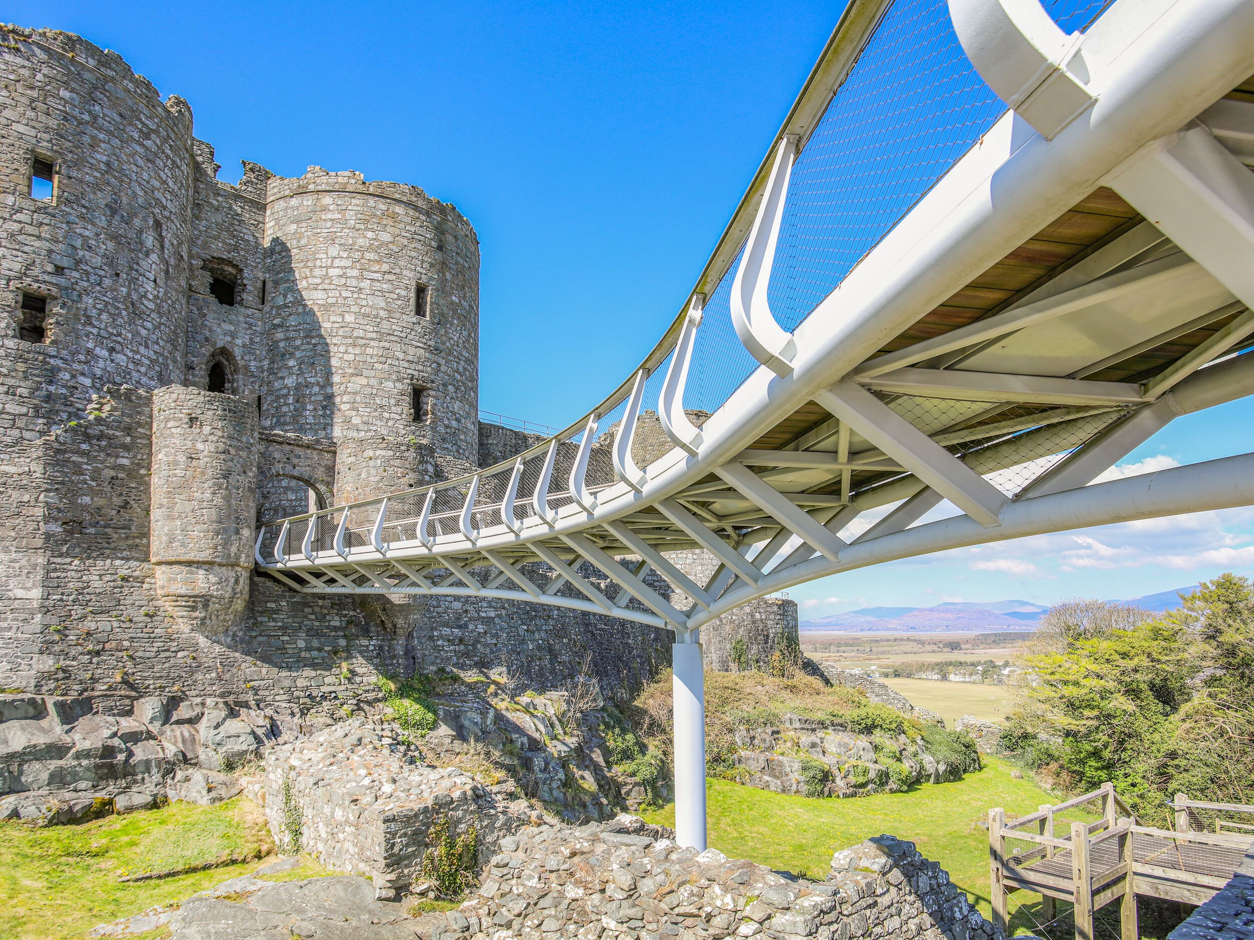 Um castelo de pedra com uma ponte pedonal moderna.