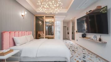 Quarto moderno com uma cama grande, televisão na parede e um candelabro singular.