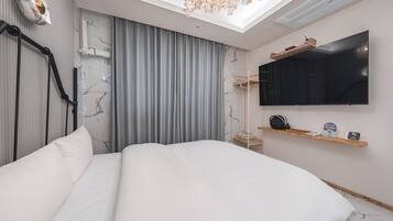 Quarto moderno com uma cama grande, televisão de tela plana na parede e uma clarabóia.