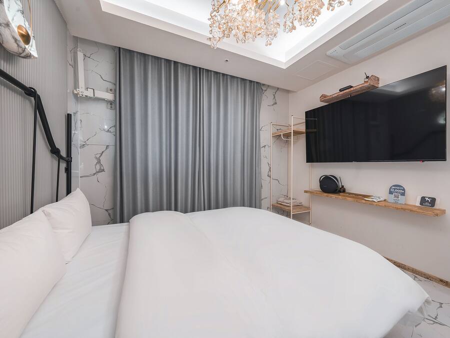 Quarto moderno com uma cama grande, televisão de tela plana na parede e uma clarabóia.
