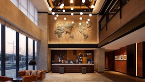 Um lobby moderno com uma mesa de recepção, grandes janelas e um mural de um mapa-múndi.