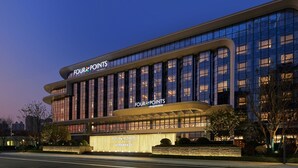 Um hotel moderno com uma placa chamativa 'Four Points', janelas amplas e fachada bem iluminada.