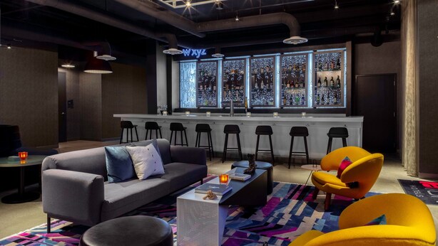 Uma área de estar moderna com um bar, sofás e banquetas.