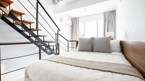 Quarto com cama, escada e janela com cortinas.