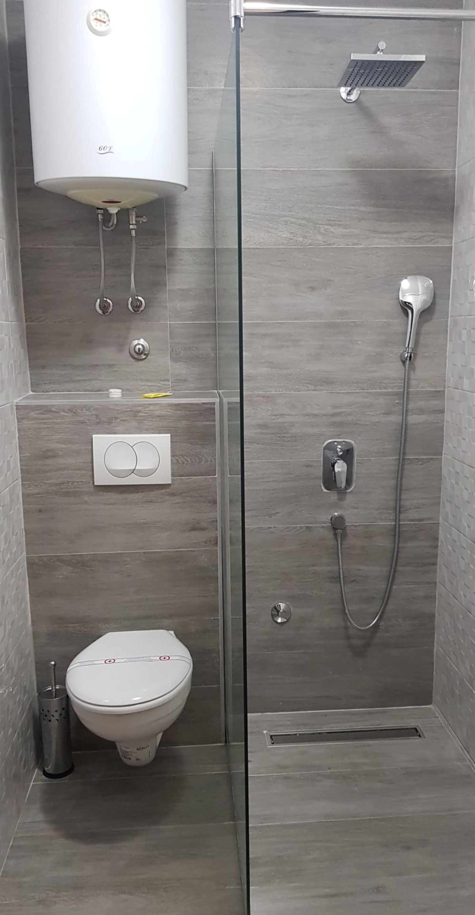 Uma casa de banho moderna com sanita, chuveiro e aquecedor embutido.