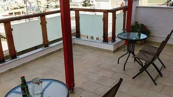 Varanda com mesa e cadeiras, com vista para o horizonte costeiro.