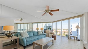 Uma sala de estar espaçosa com uma janela grande, um ventilador de teto e um sofá.