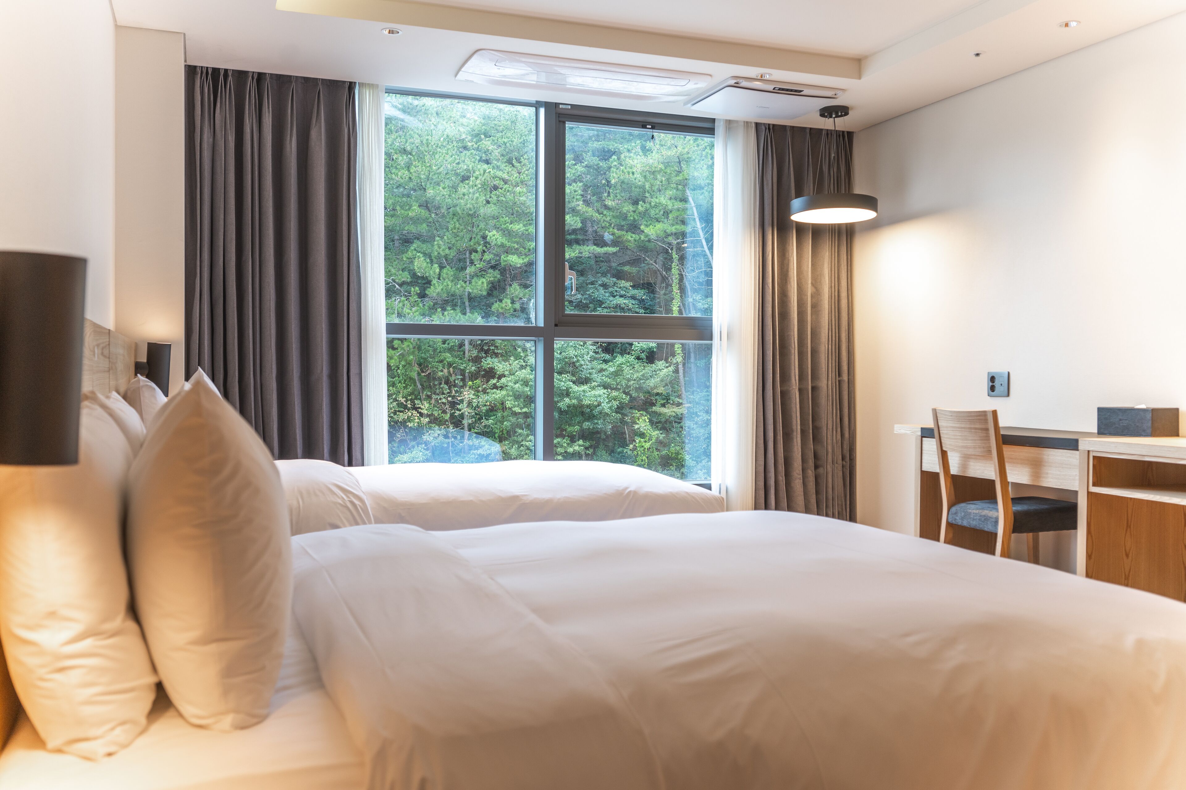 Quarto de hotel com duas camas, uma escrivaninha e uma cadeira.