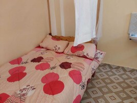 Uma cama com colcha florida e duas almofadas, um dossel branco e um piso estampado.