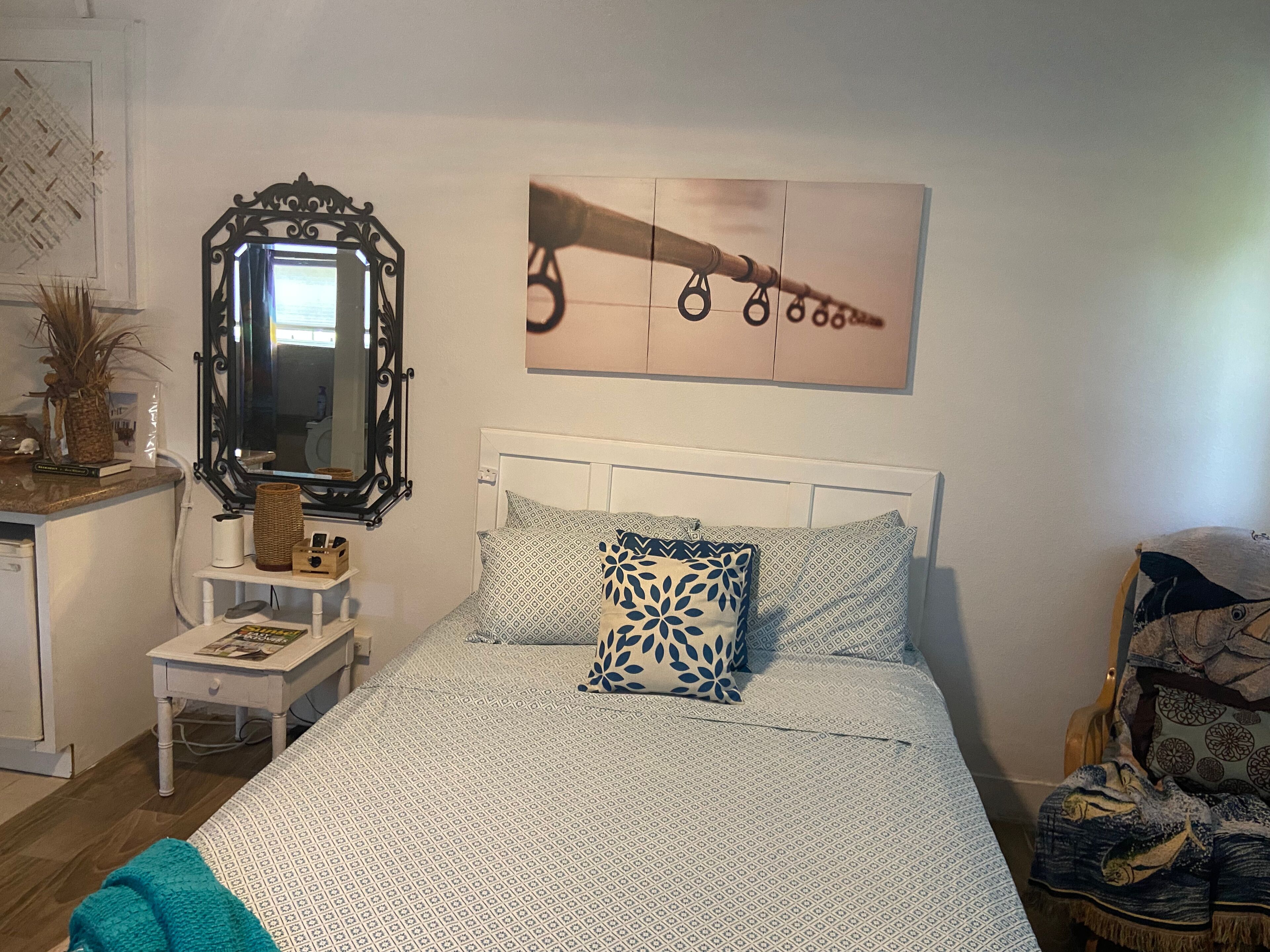 Quarto com cama, mesa de cabeceira, espelho e cadeira.