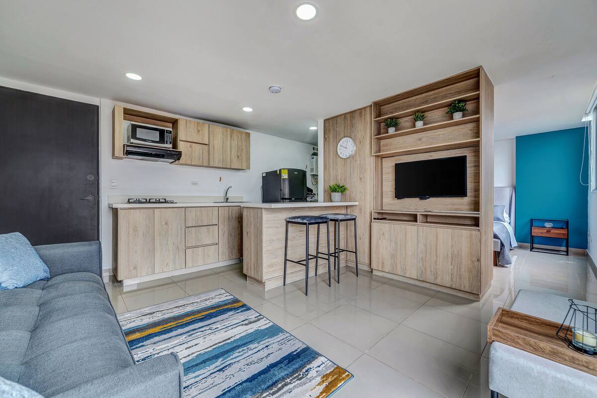 Um espaço compacto com cozinha compacta, sofá, televisão e uma pequena mesa com uma vela.