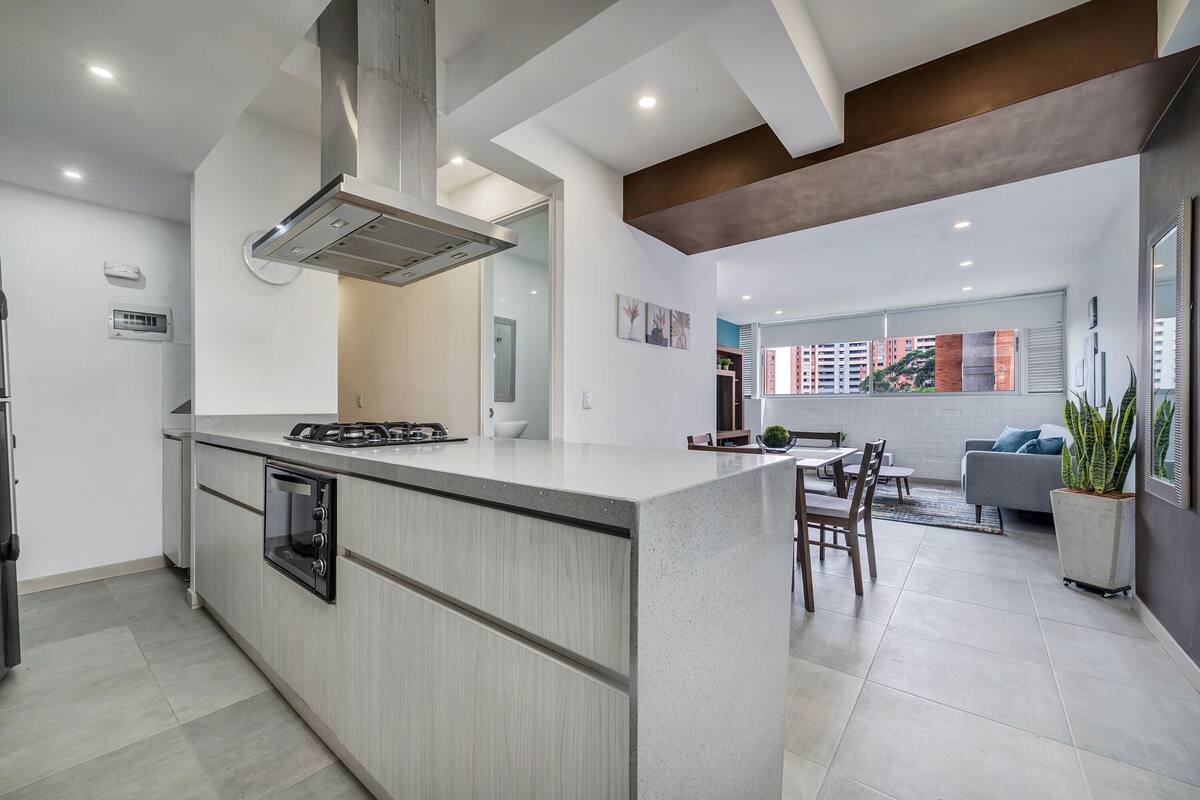 Uma cozinha moderna com uma ilha central, forno embutido e exaustor de aço inoxidável.
