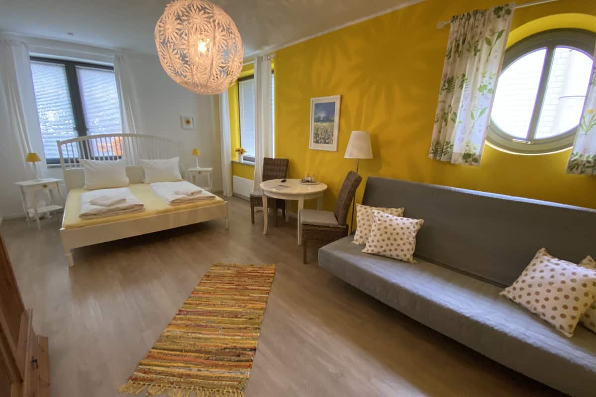 Quarto com cama, sofá, mesa de jantar e luminária pendente.