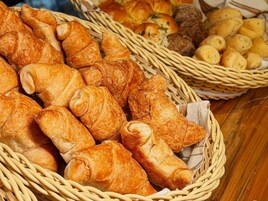 Uma cesta com diversos pães e produtos de pastelaria, incluindo croissants.